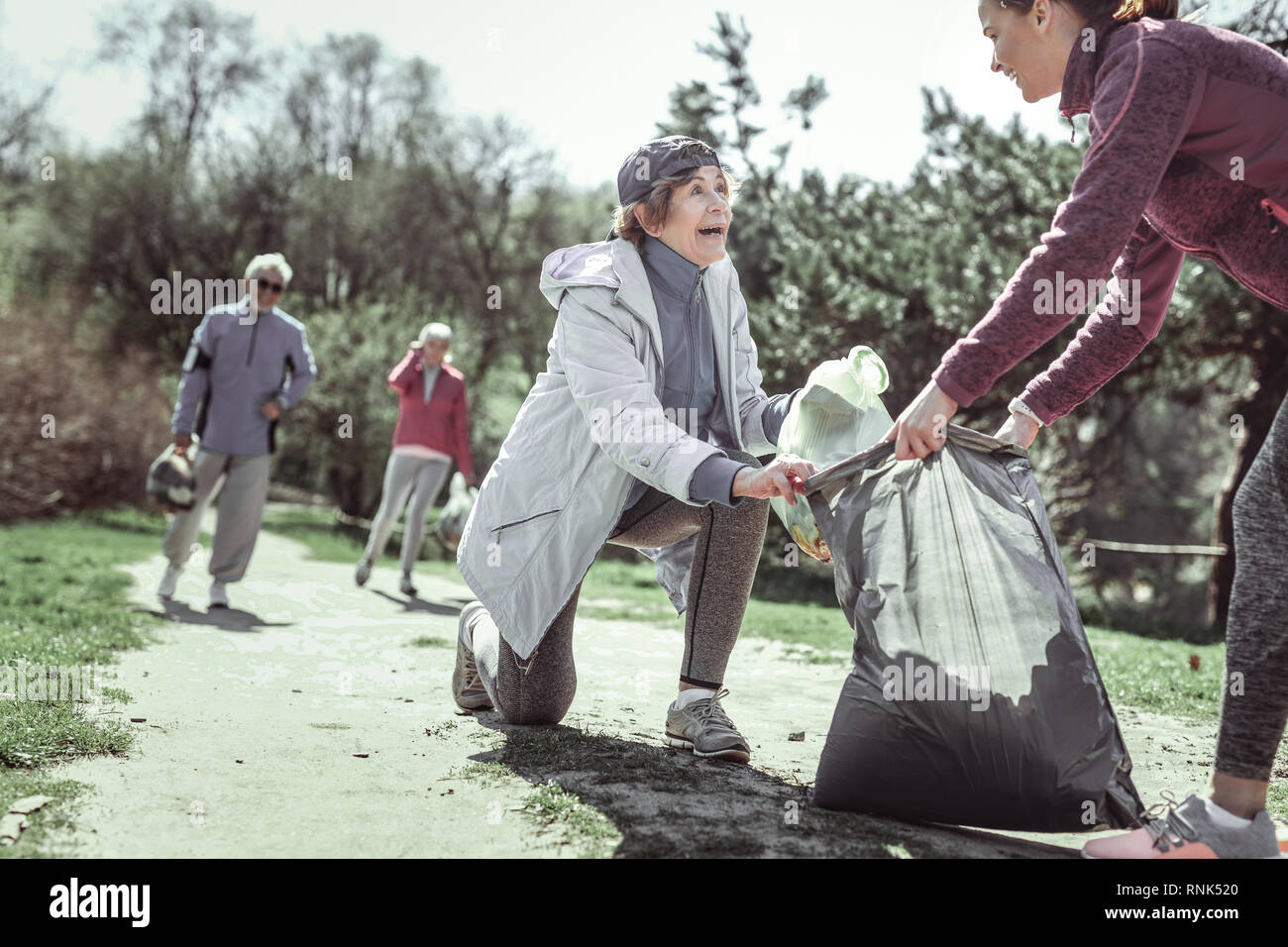 Young smiling curator giving big trash packet Stock Photo - Alamy