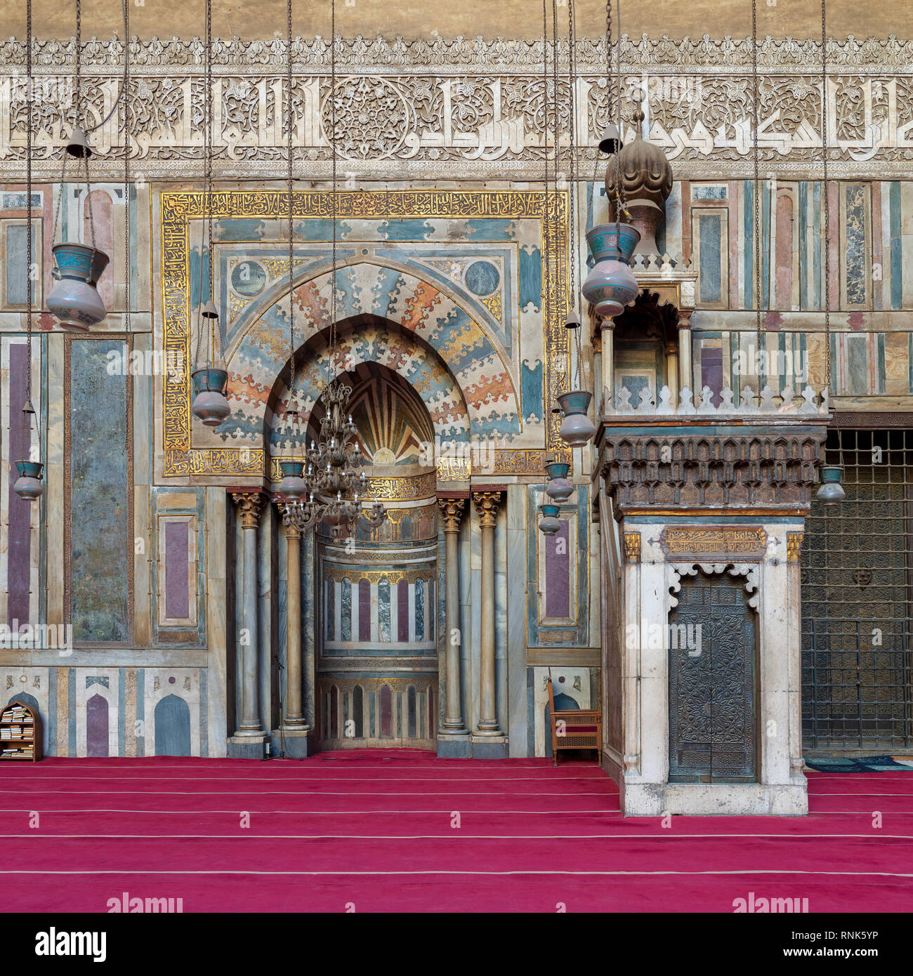 Colorful decorated marble wall with engraved Mihrab (niche) and wooden ...