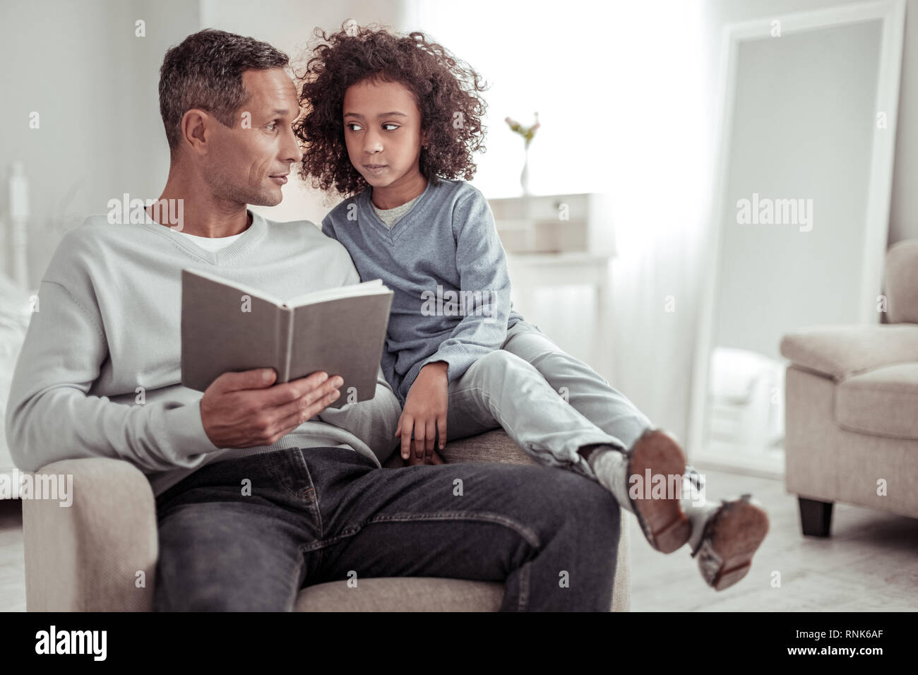 Serious father and daughter reading a book together Stock Photo - Alamy
