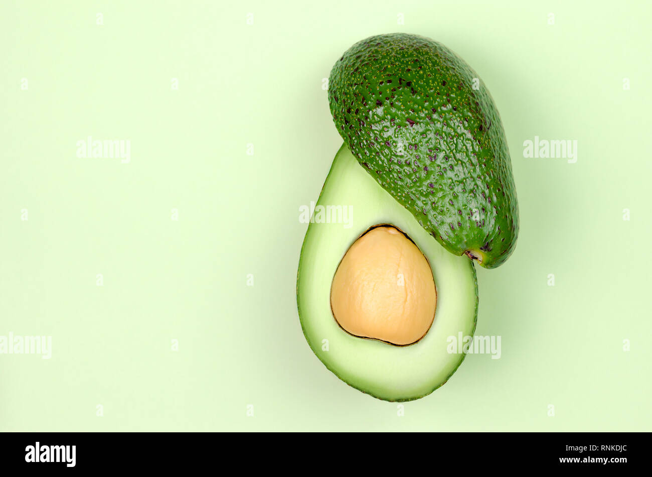 Fresh green avocado on light green background Stock Photo - Alamy