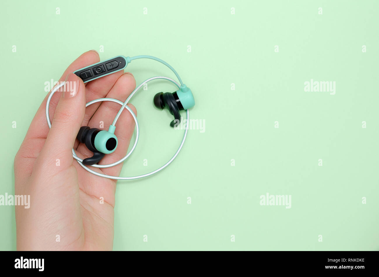 Green wireless headphones on light green background Stock Photo - Alamy