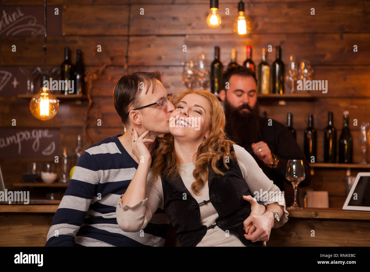 Young couple sitting at bar counter and showing affection. Having fun ...