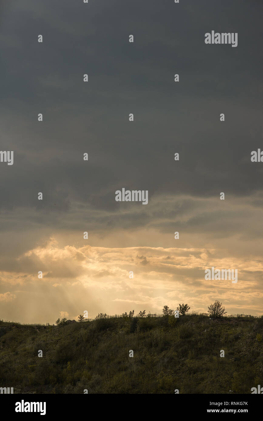 Spring landscape of grassy hill against a dramatic sunset sky with ...