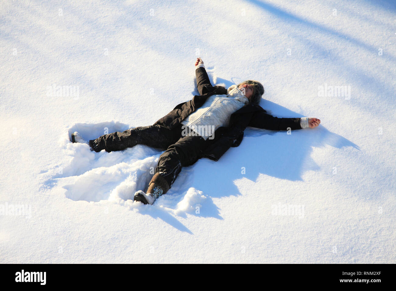 Adult woman lying on clear snow Stock Photo - Alamy
