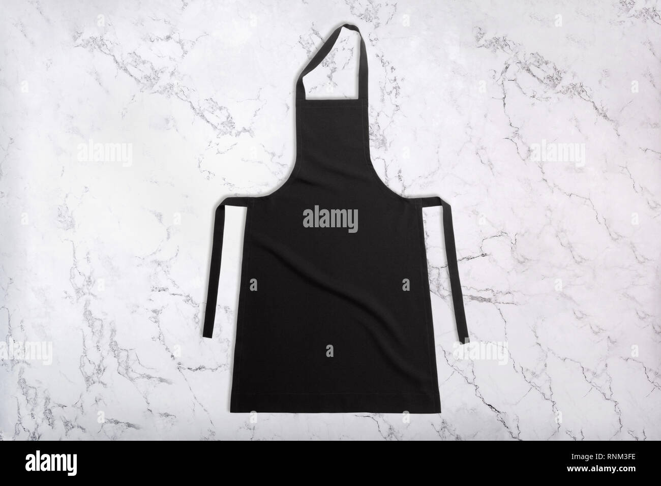 Flat lay of black apron on white marble texture. Apron on marble ...