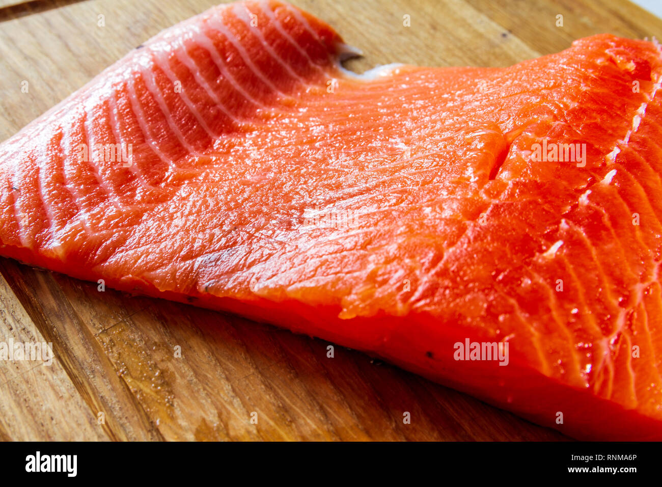 Large fillet cut of dark red Atlantic Salmon isolated on a wood ...