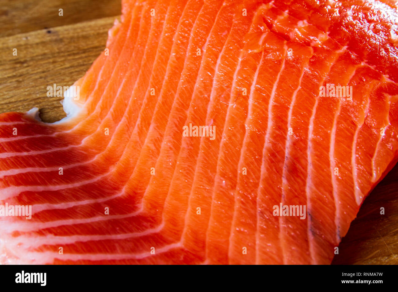 Large fillet cut of dark red Atlantic Salmon isolated on a wood ...