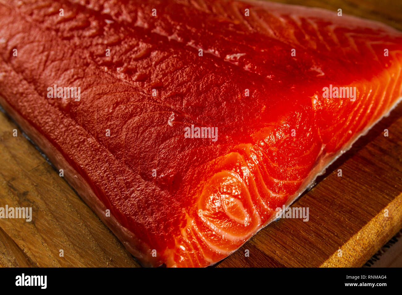 Large fillet cut of dark red Atlantic Salmon isolated on a wood ...