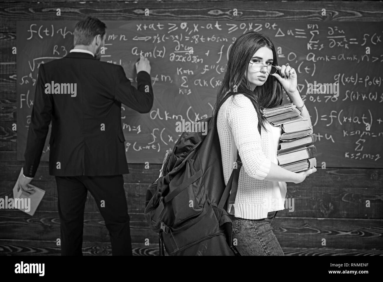 Brunette student with heap of books and heavy rucksack holding her ...