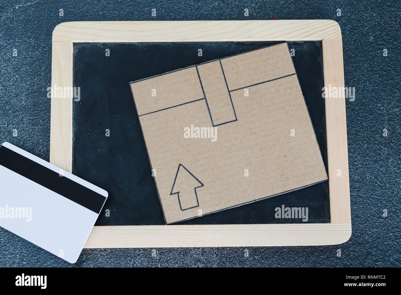 cardboard parcel with blackboard and payment card on concrete desk ...