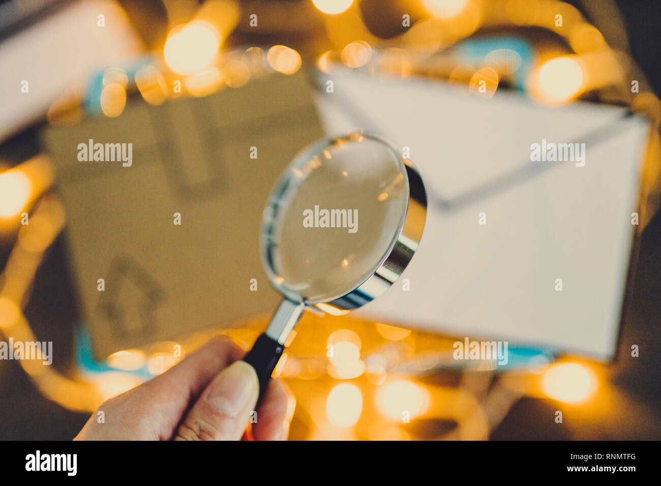 hand holding magnifying glass over shopping cart with cardboard parcel ...