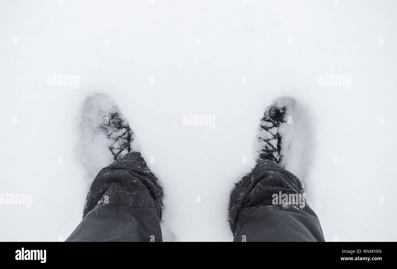 Top view of male feet in black shoes standing in deep snow, first ...
