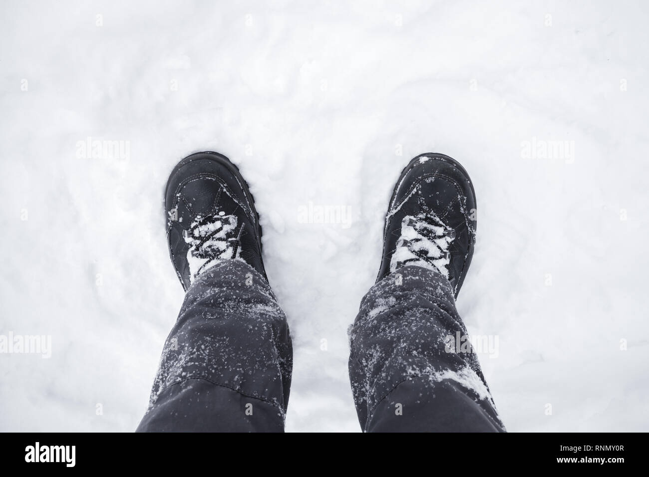 Close up photo of male feet in black shoes standing on snowy ground ...
