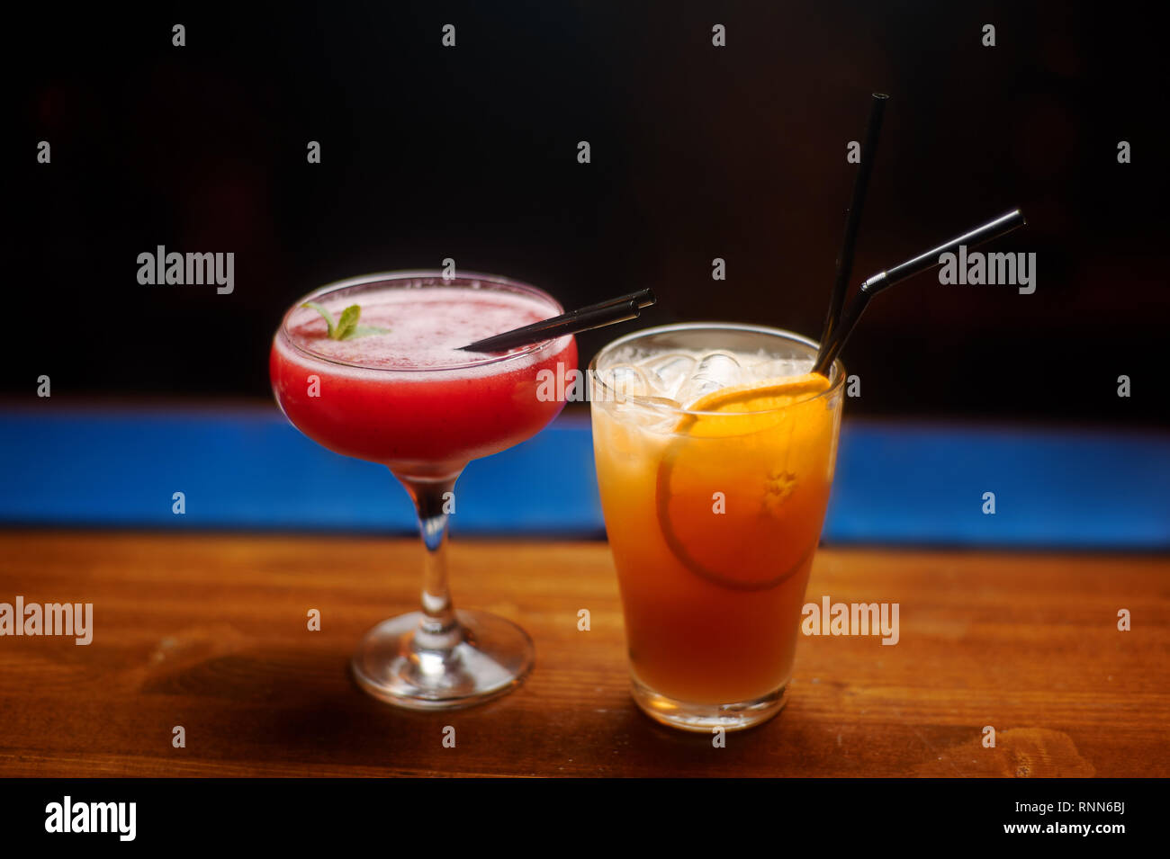 two cocktails at bar counter. red and orange alcohol drinks Stock Photo ...