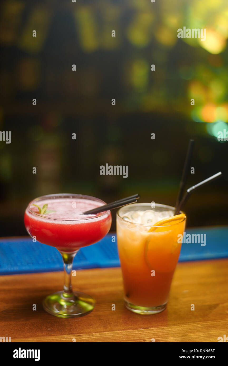 two cocktails at bar counter. red and orange drinks. vertical Stock ...