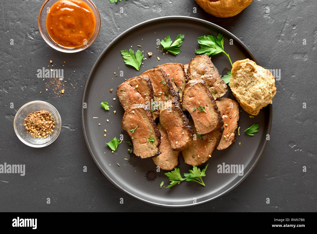 Beef liver on plate over black stone background. Sliced grilled liver ...
