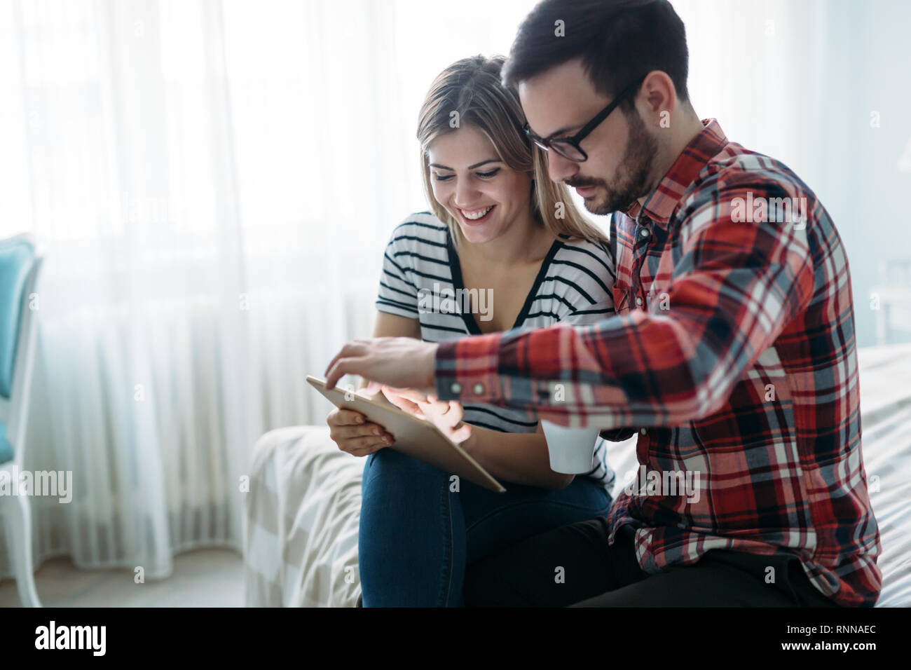 Young happy couple using tablet in bedroom Stock Photo - Alamy