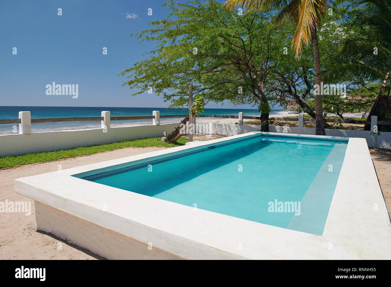 Swimming pool on beach shore with blue water in tropical resort Stock ...