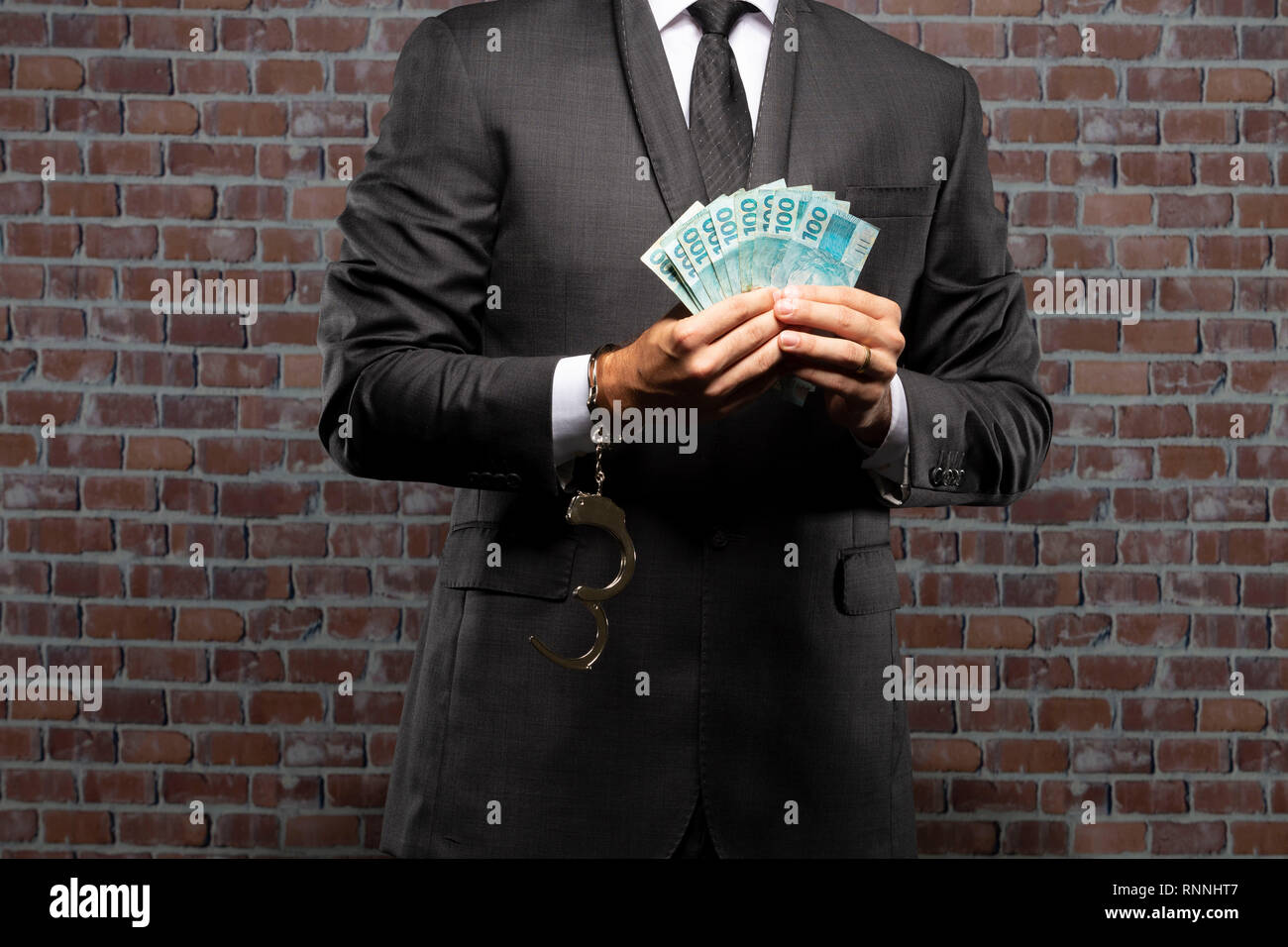 Brazilian man holding bills of money with a handcuff in a jail. concept ...