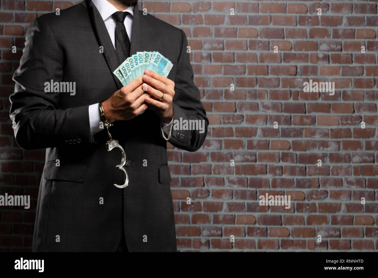 Brazilian man holding bills of money with a handcuff in a jail. concept ...