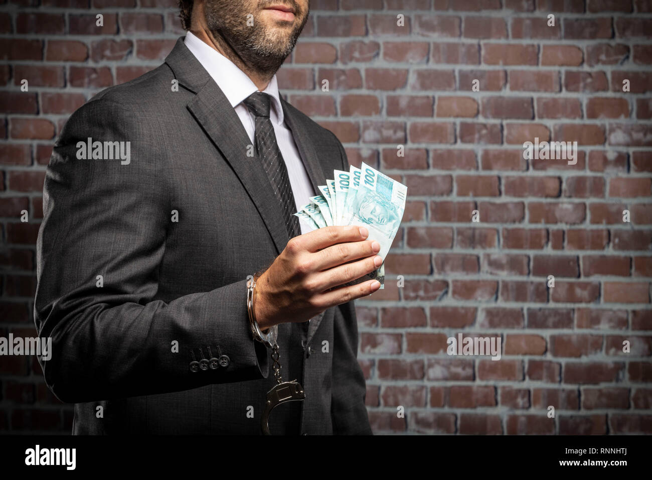 Brazilian man holding bills of money with a handcuff in a jail. concept ...