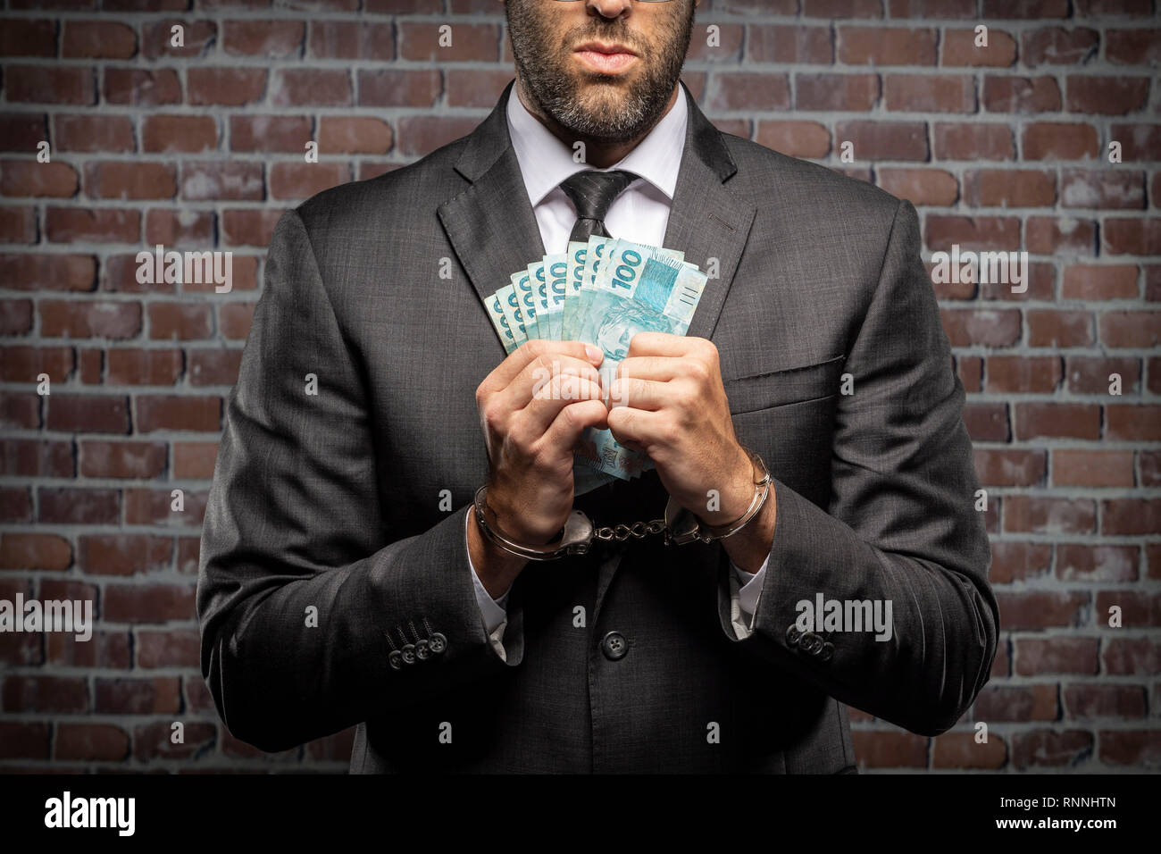 Brazilian man holding bills of money with a handcuff in a jail. concept ...