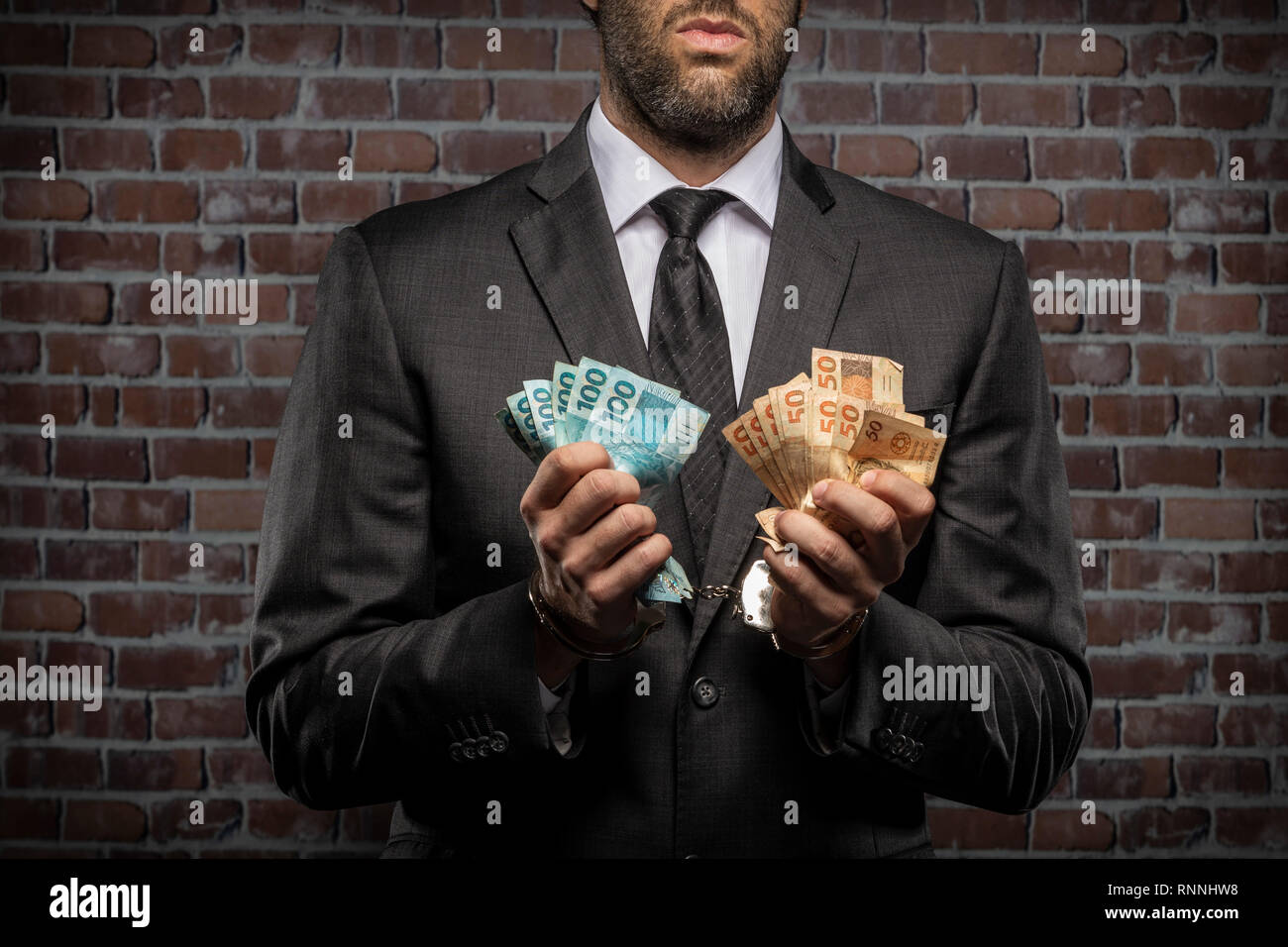 Brazilian man holding bills of money with a handcuff in a jail. concept ...