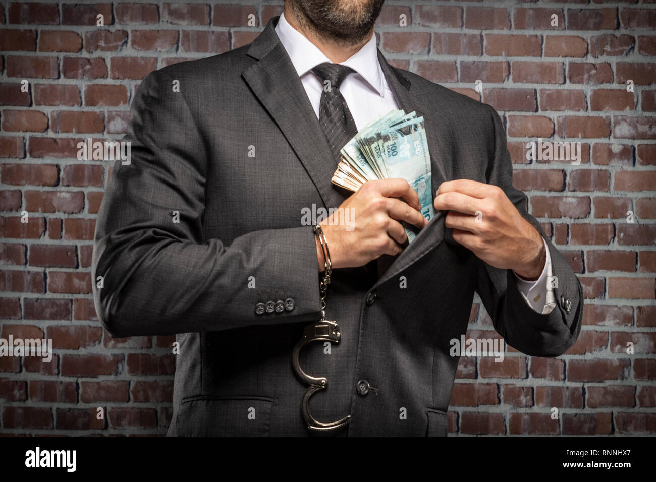 Brazilian man holding bills of money with a handcuff in a jail. concept ...