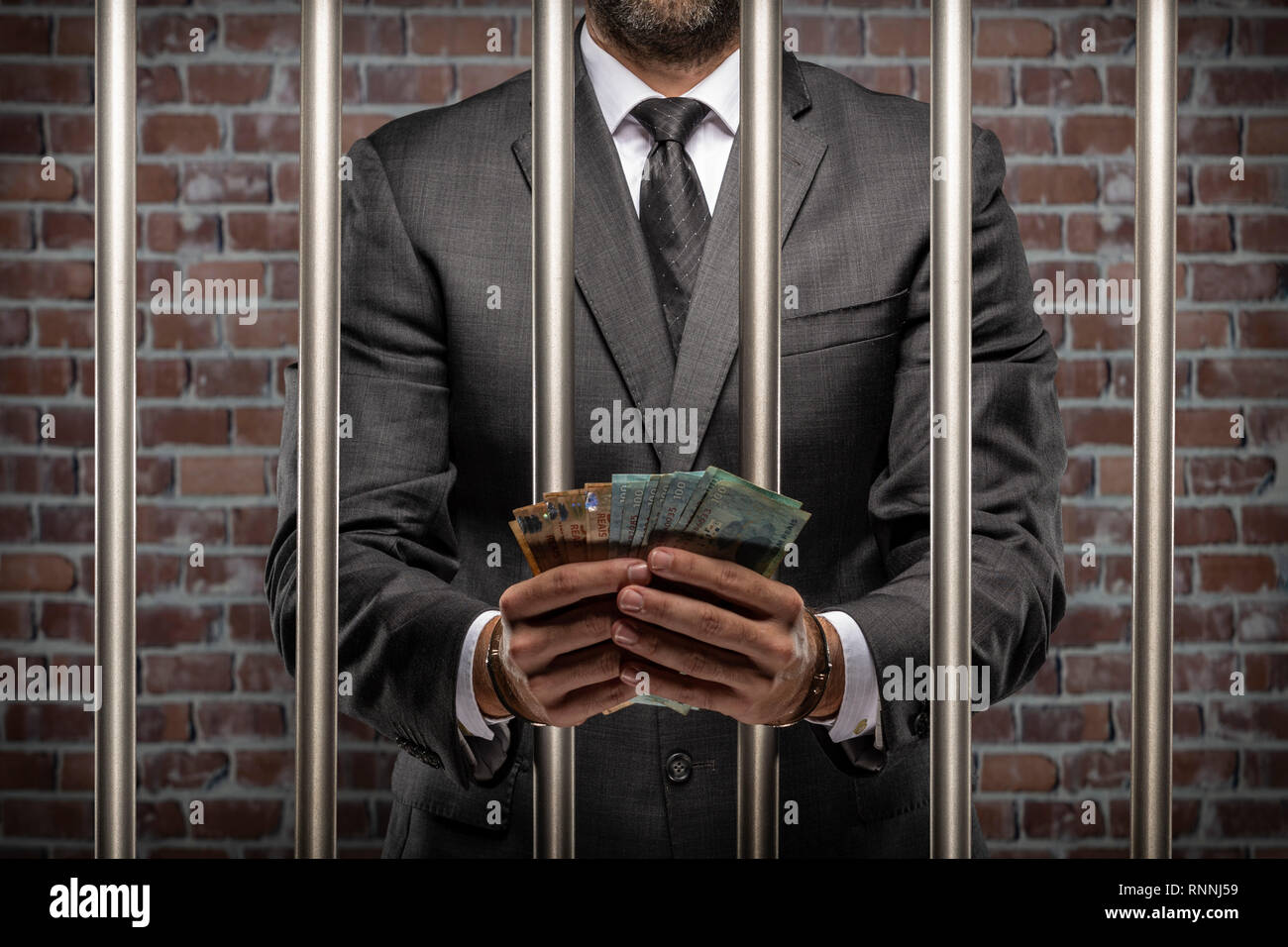 Brazilian man holding bills of money with a handcuff in a jail. concept ...