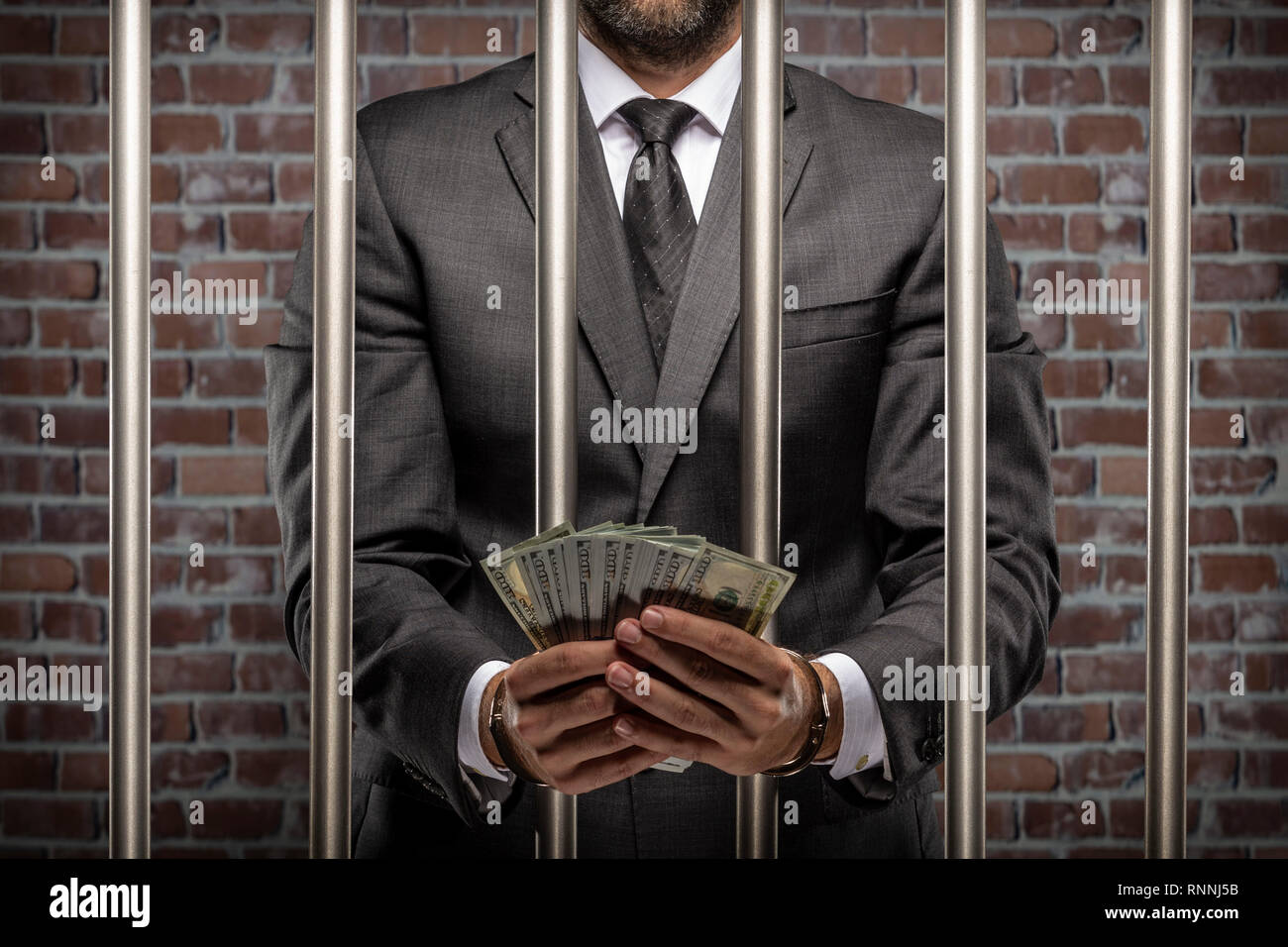 Brazilian man holding bills of money with a handcuff in a jail. concept ...