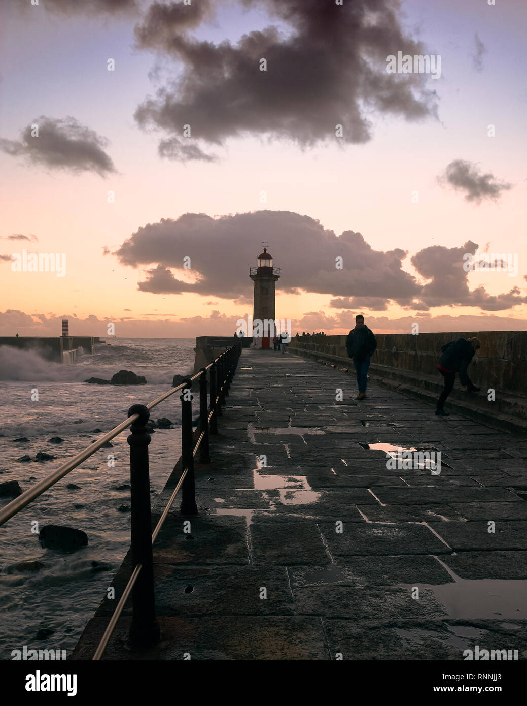 Lighthouse on the end of the jetty at sunsethour Stock Photo - Alamy