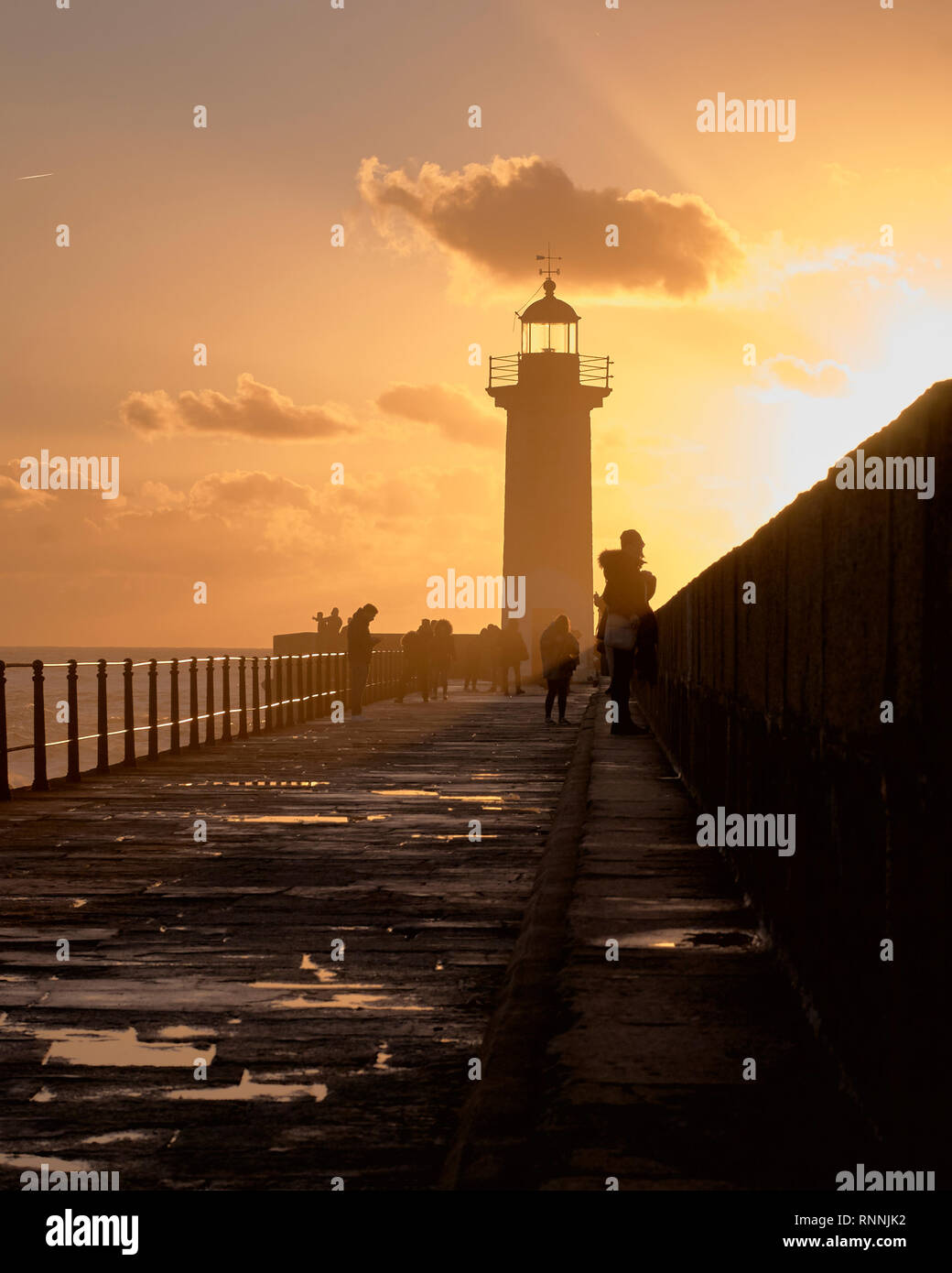Lighthouse on the end of the jetty at sunsethour Stock Photo - Alamy