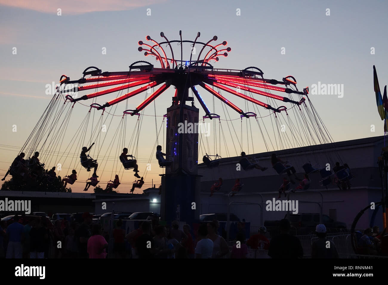Ferris wheel and giant swings in an amusement park at sunset Stock ...
