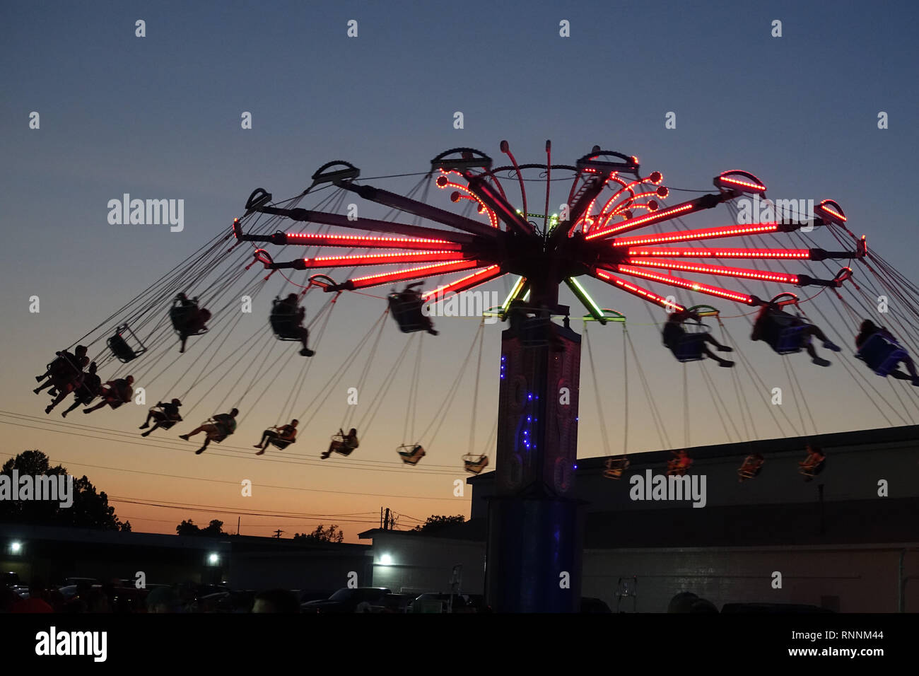 Ferris wheel and giant swings in an amusement park at sunset Stock ...