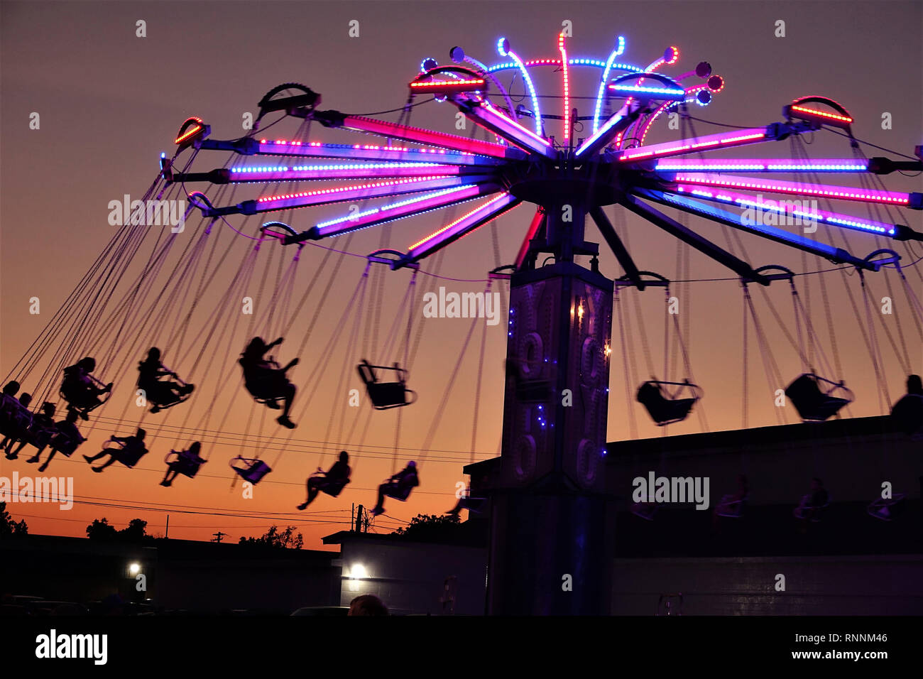 Ferris wheel and giant swings in an amusement park at sunset Stock ...