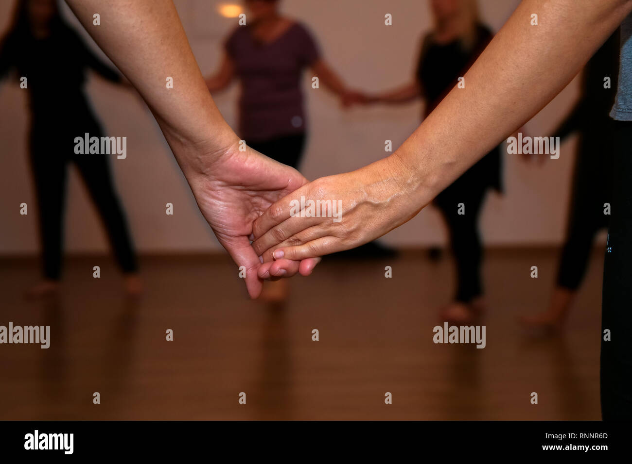 Two women holding hands during a women's dance circle Stock Photo - Alamy