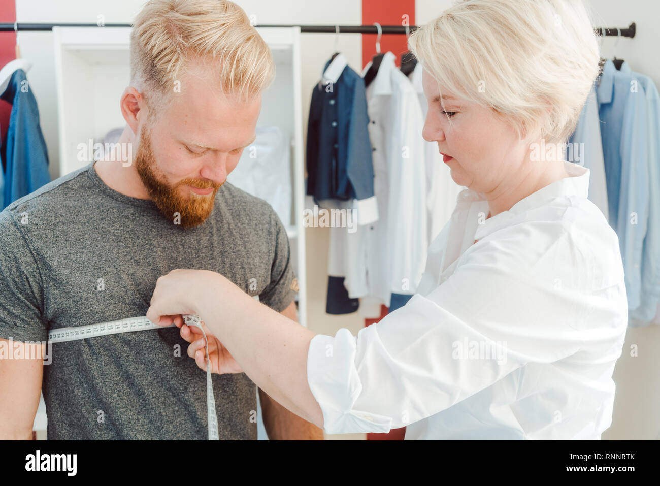 Tailor measuring customer with measuring tape Stock Photo - Alamy