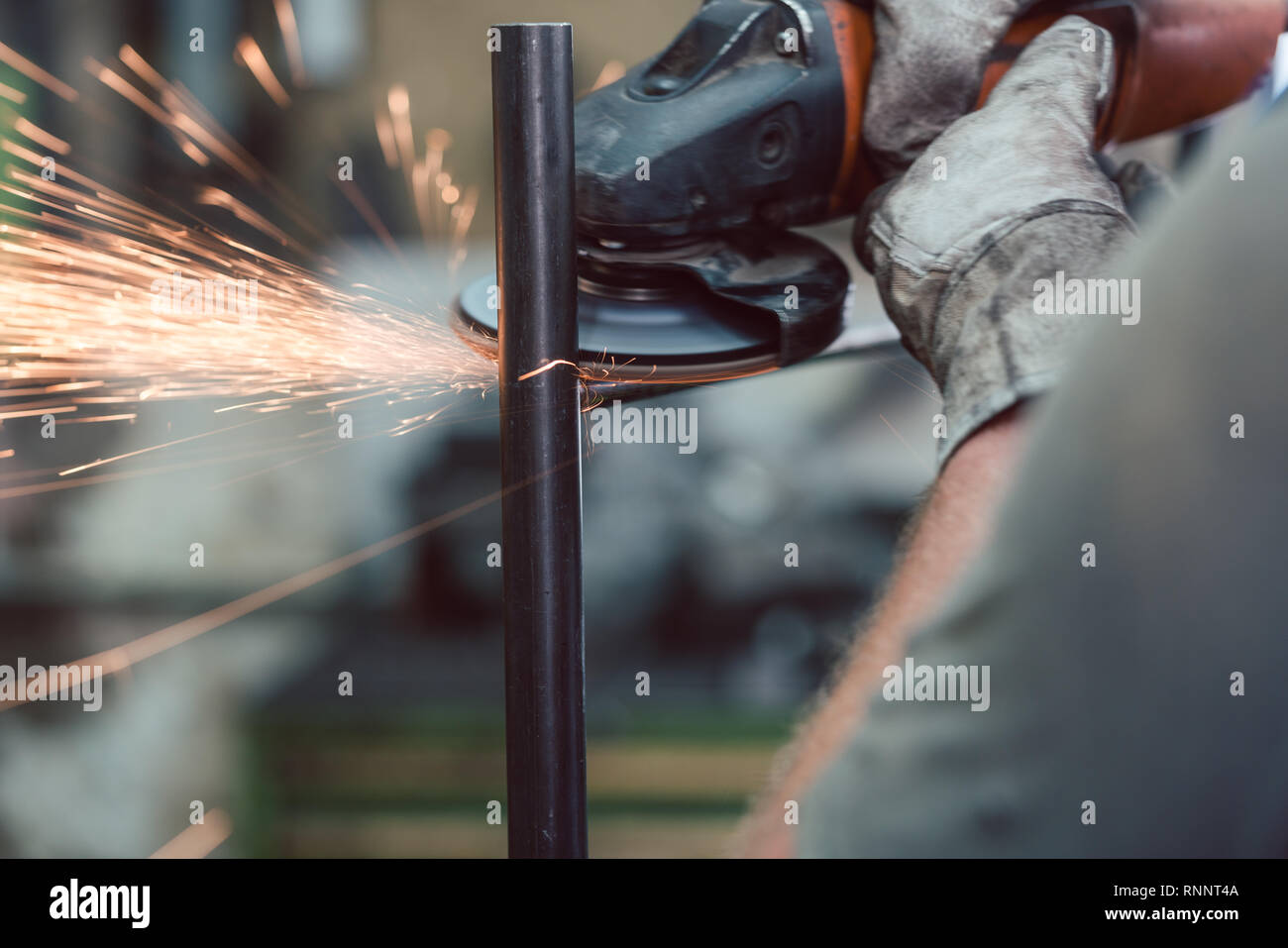 Worker in metal factory grinding workpiece with sparks flying Stock ...