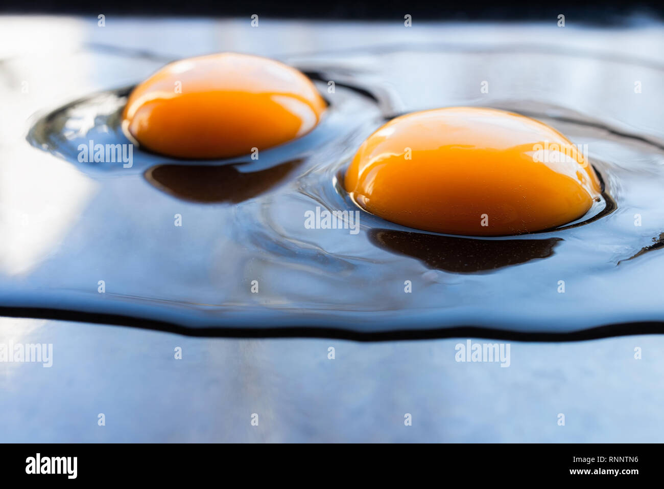 Two fresh raw chicken eggs spilled on a pan Stock Photo - Alamy