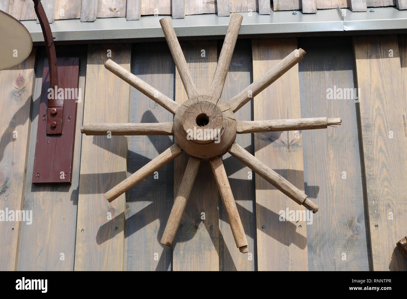 Old oak wheel from a rustic cart hanging on the wall of a barn. Sunny ...