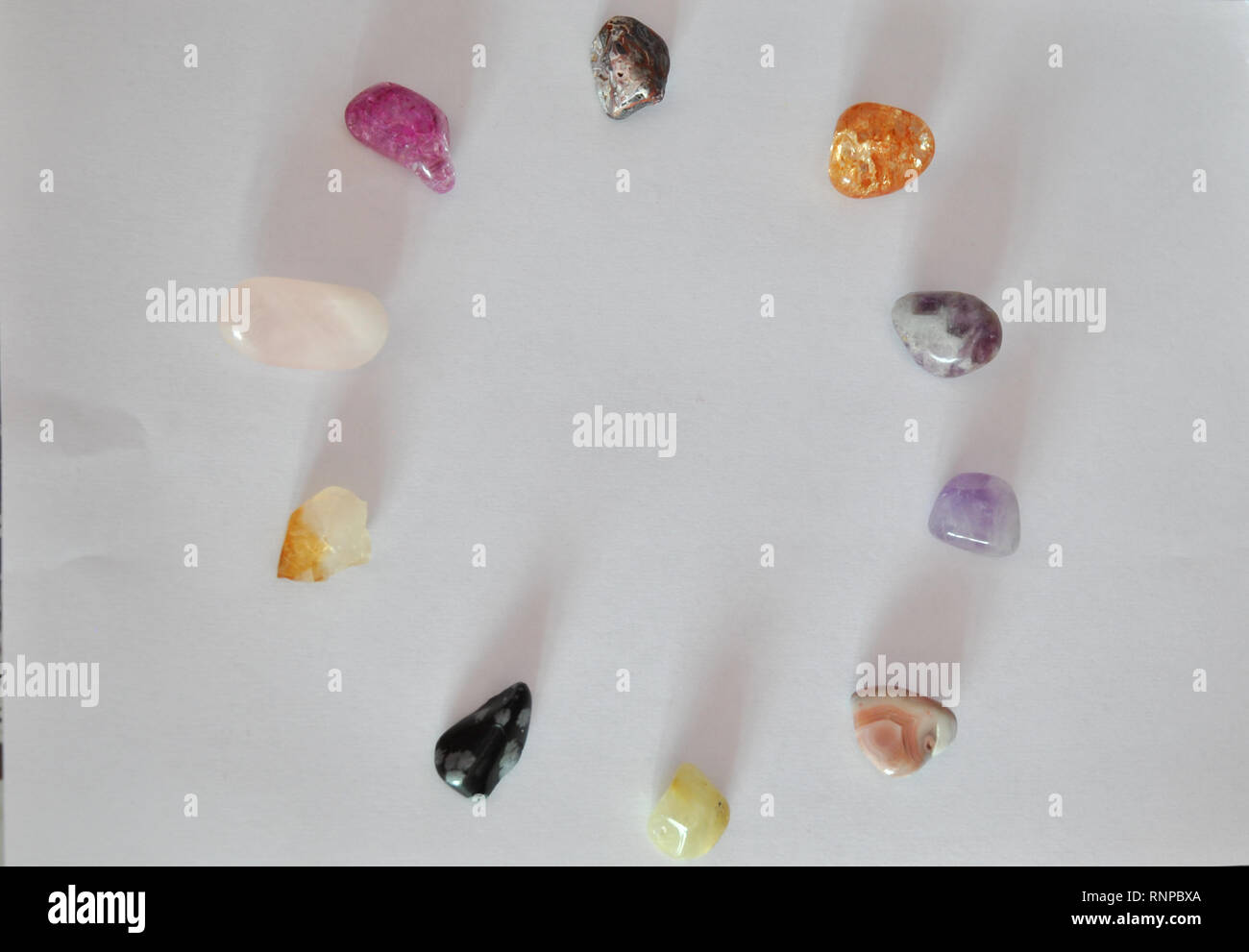 A circle of different types of polished stones on a white background ...