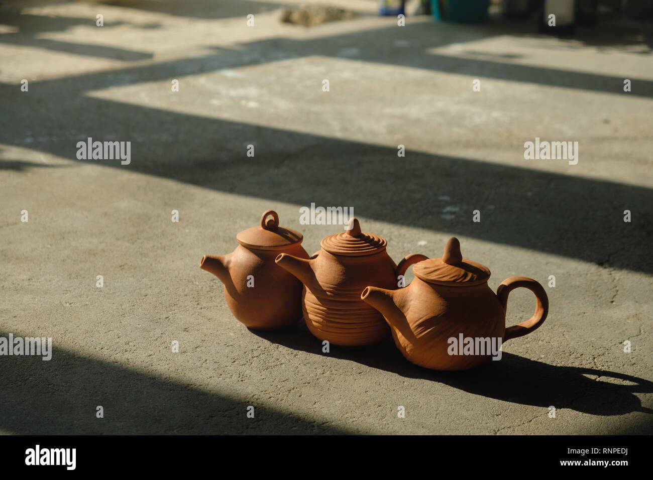 Three ceramic pottery tea pots made from clay drying in the sun. Clay ...