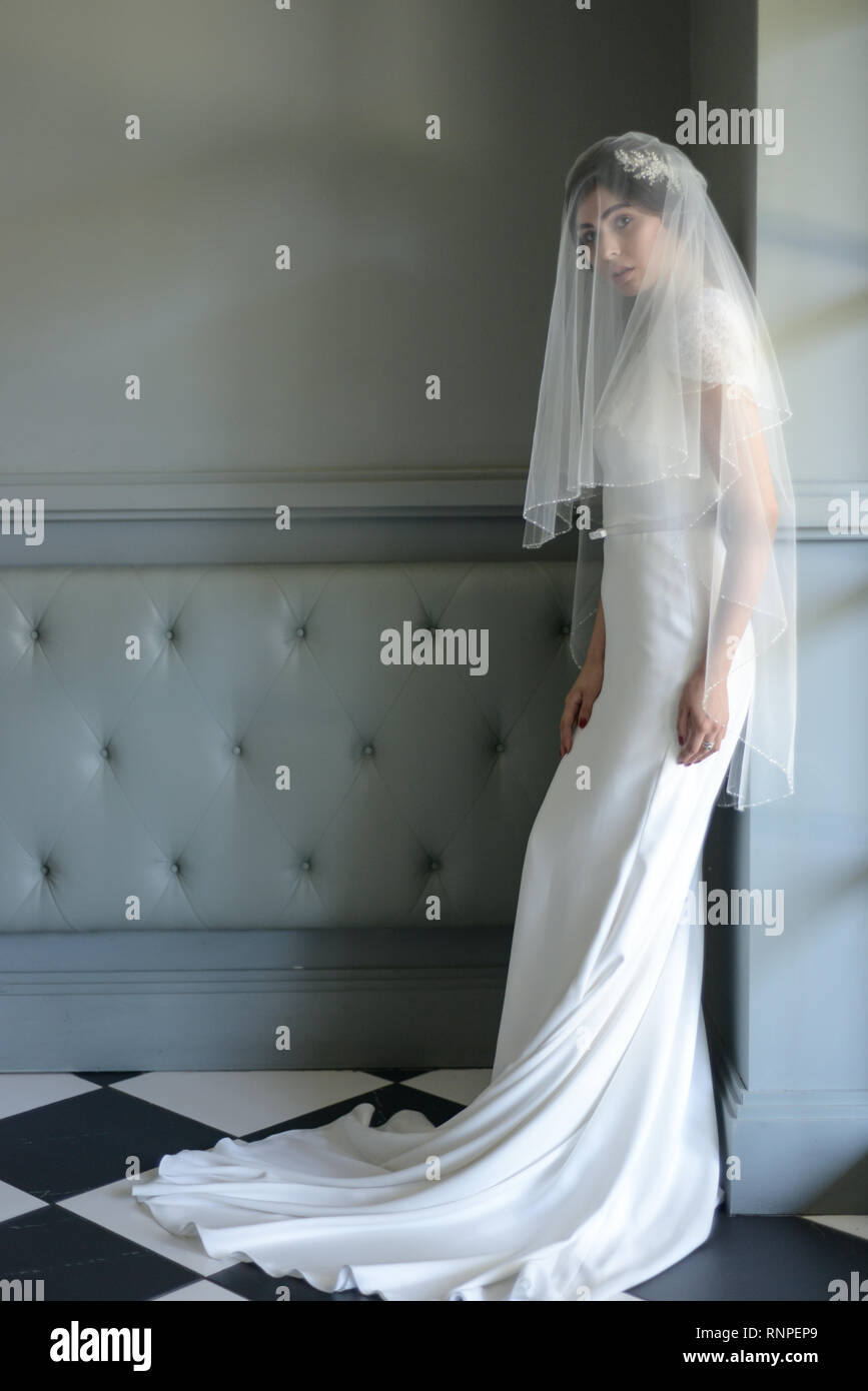 A young pensive couple have a traditional English White Wedding, they are both dark haired and ...