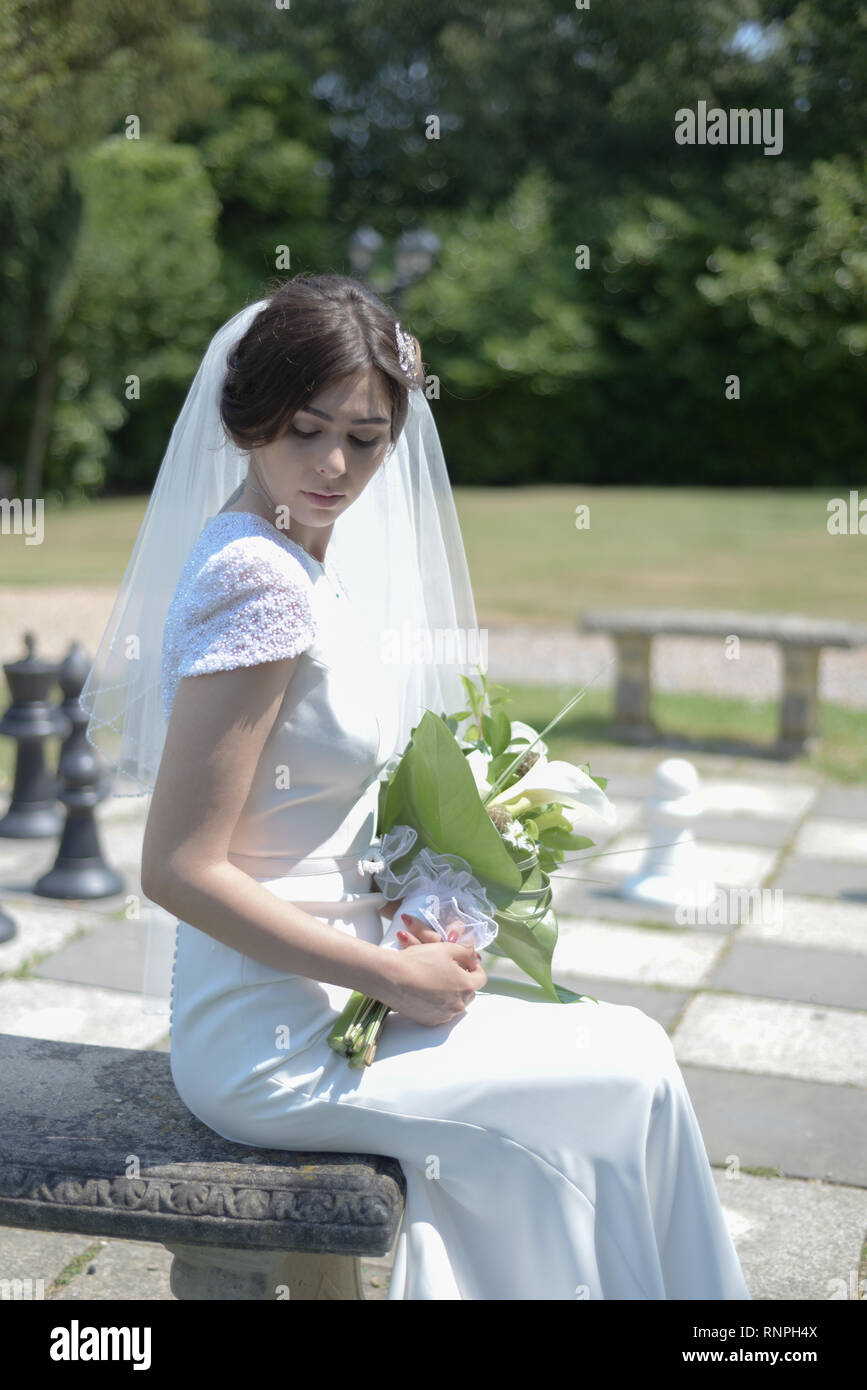 A young pensive couple have a traditional English White Wedding, they are both dark haired and ...