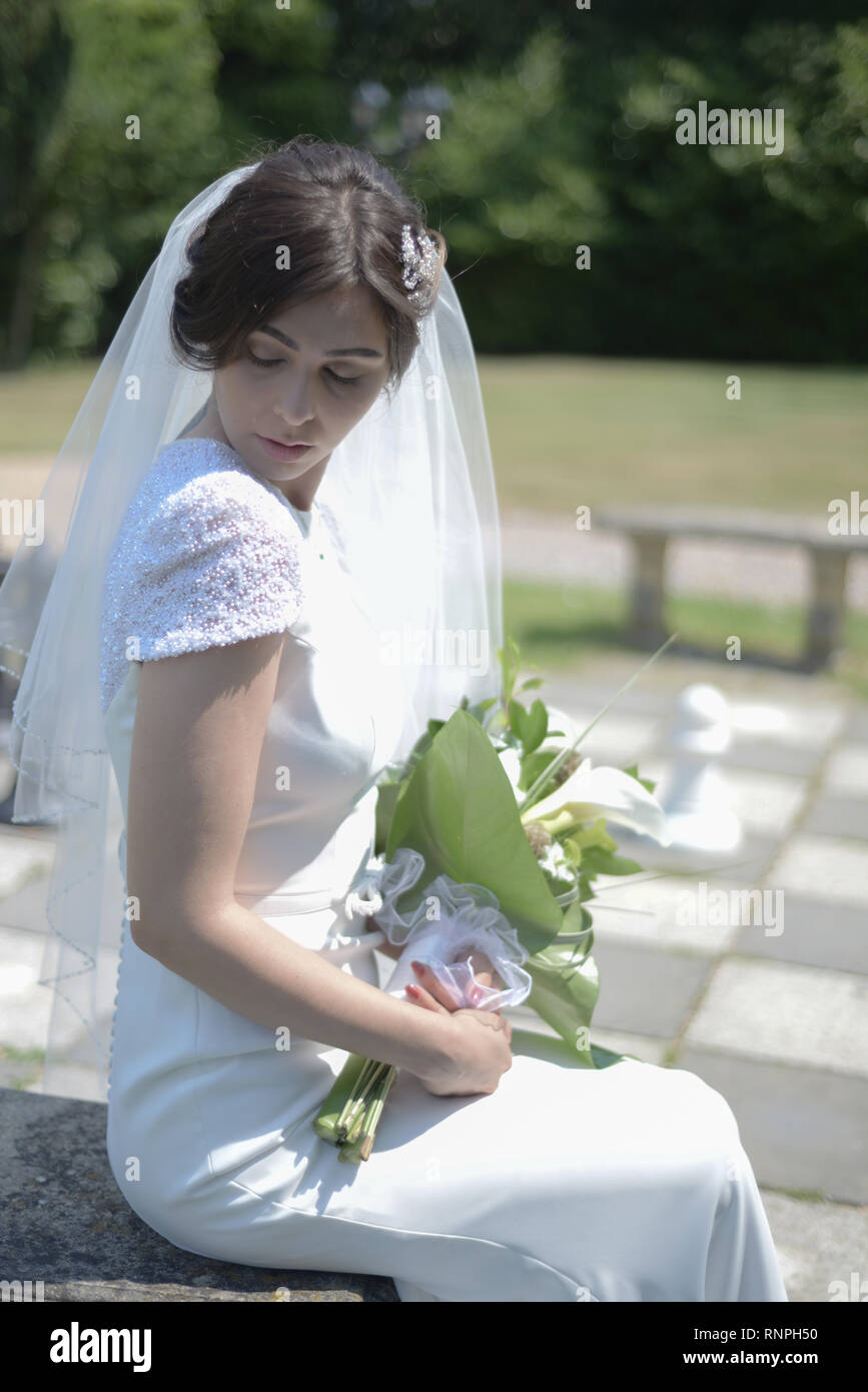 A young pensive couple have a traditional English White Wedding, they are both dark haired and ...
