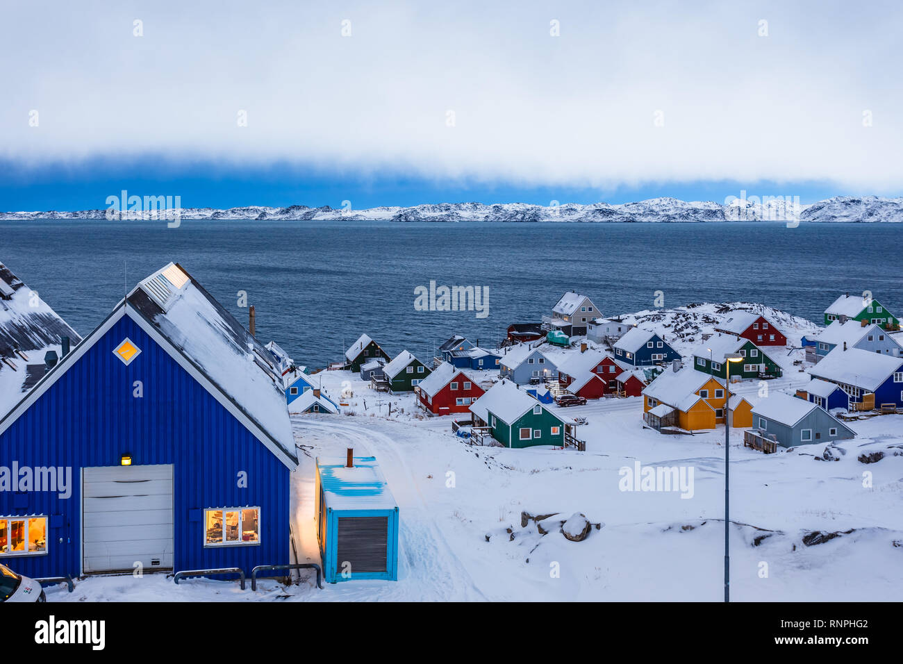 Colorful inuit huts among rocks and snow at the fjord in a suburb of ...