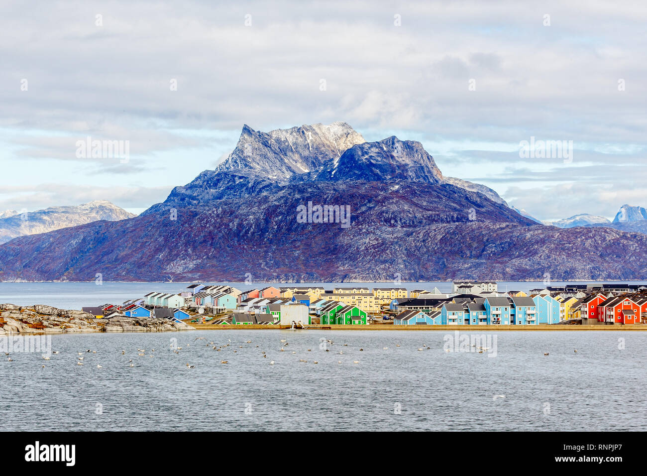 Colorful Inuit buildings in residential district of Nuuk city with lake in the foreground and ...