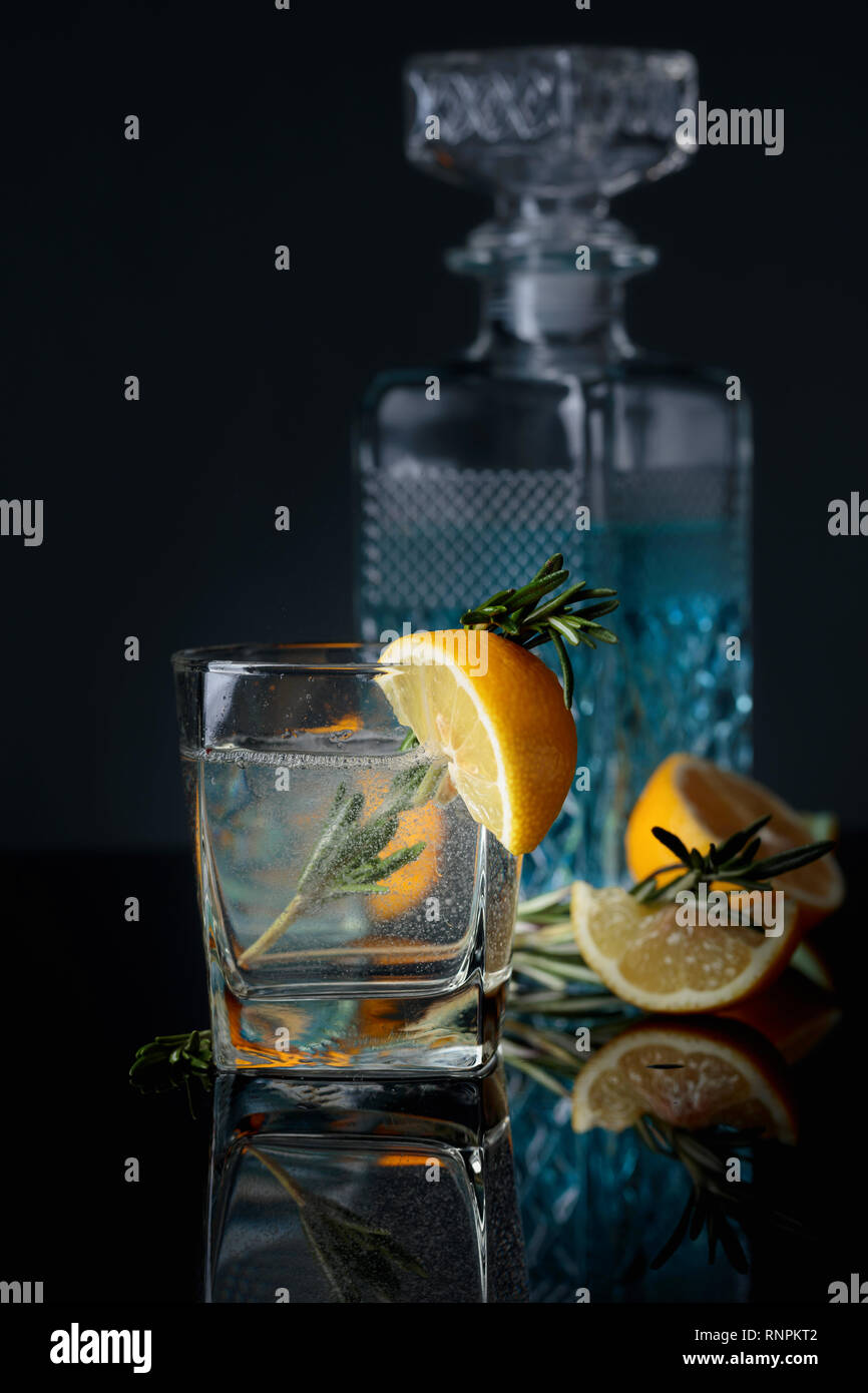 Cocktail gin-tonic with lemon slices and twigs of rosemary on a black ...