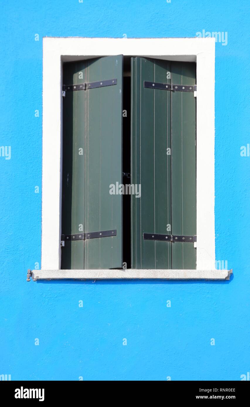 single rectangular window with closed shutters and light blue wall ...