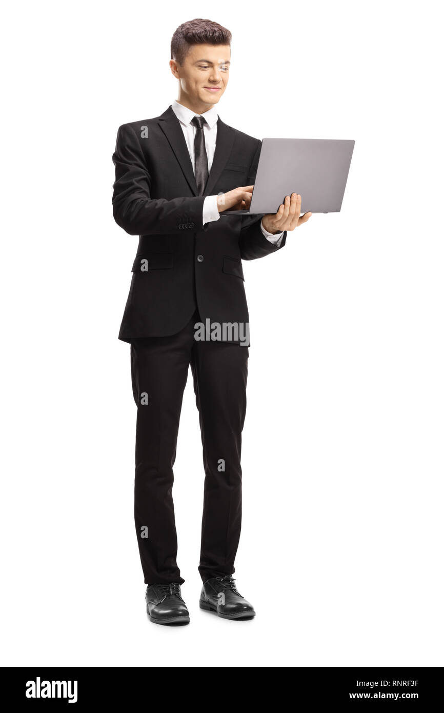 Full length portrait of a young man in a suit standing and typing on a ...